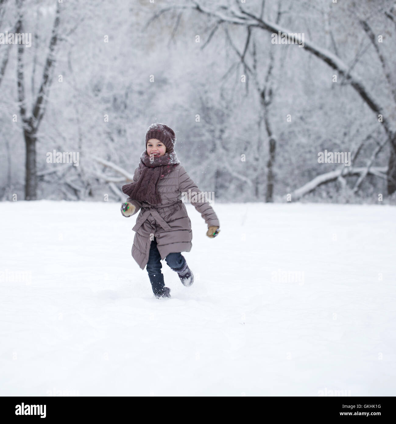 Little girl running on the background of snow covered winter park Stock ...