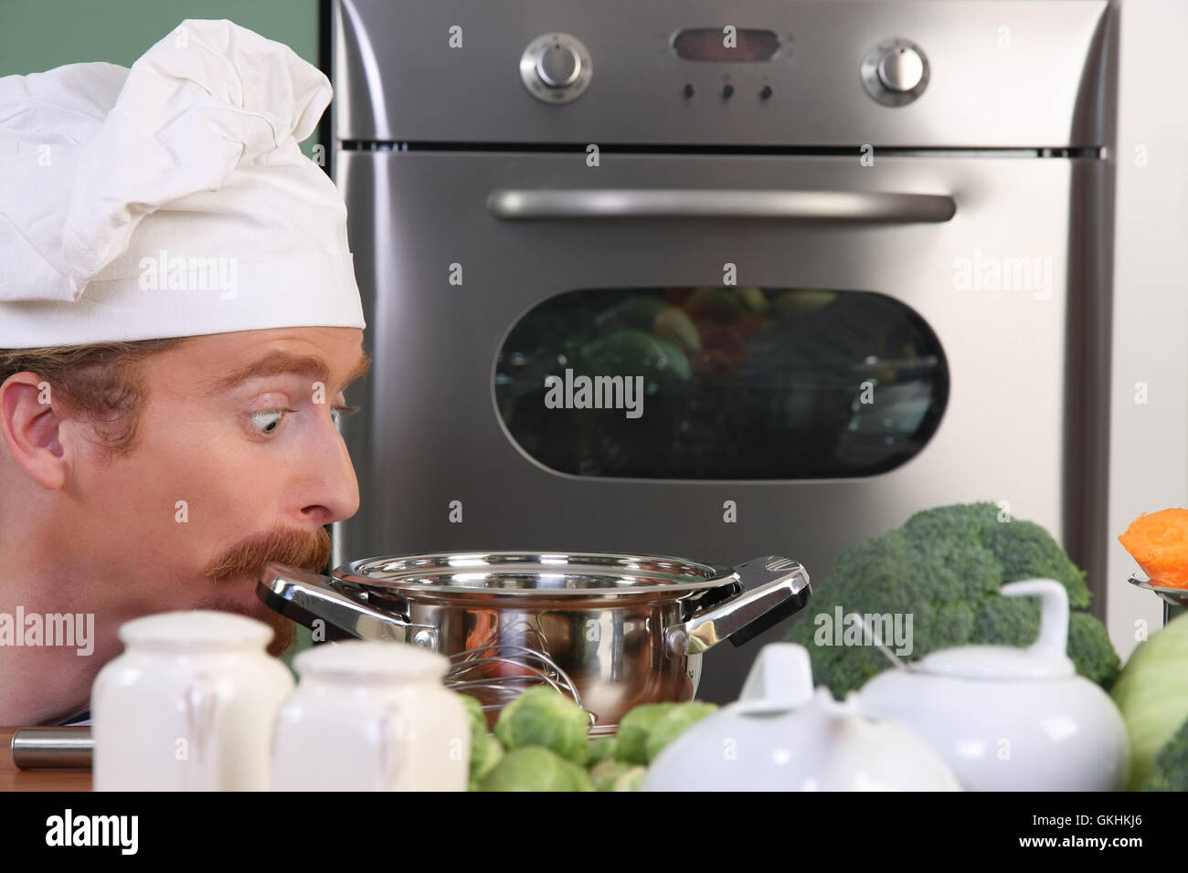 Funny young chef strange looking at pot Stock Photo - Alamy