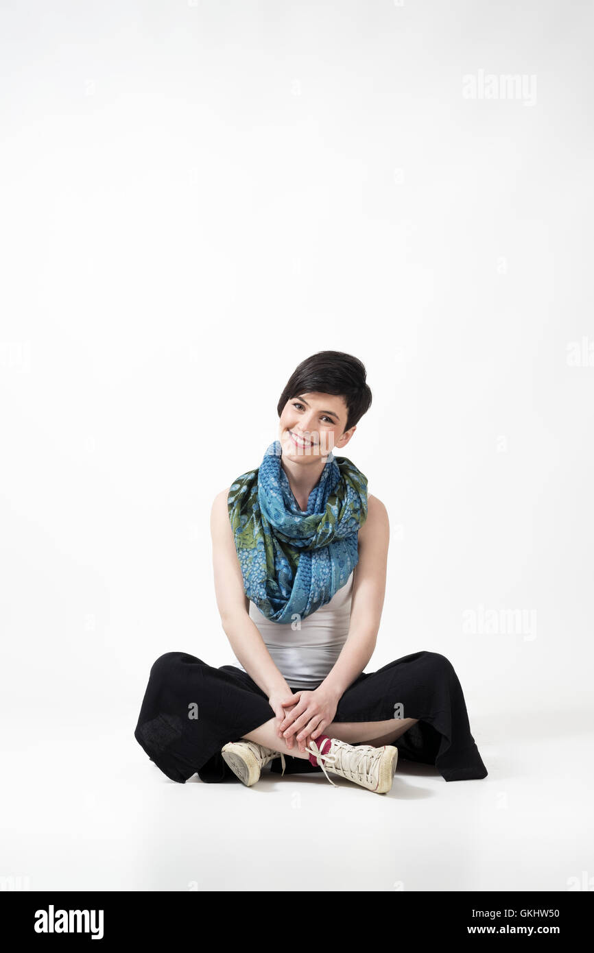 Cute pretty woman sitting with crossed legs and smiling at camera over ...