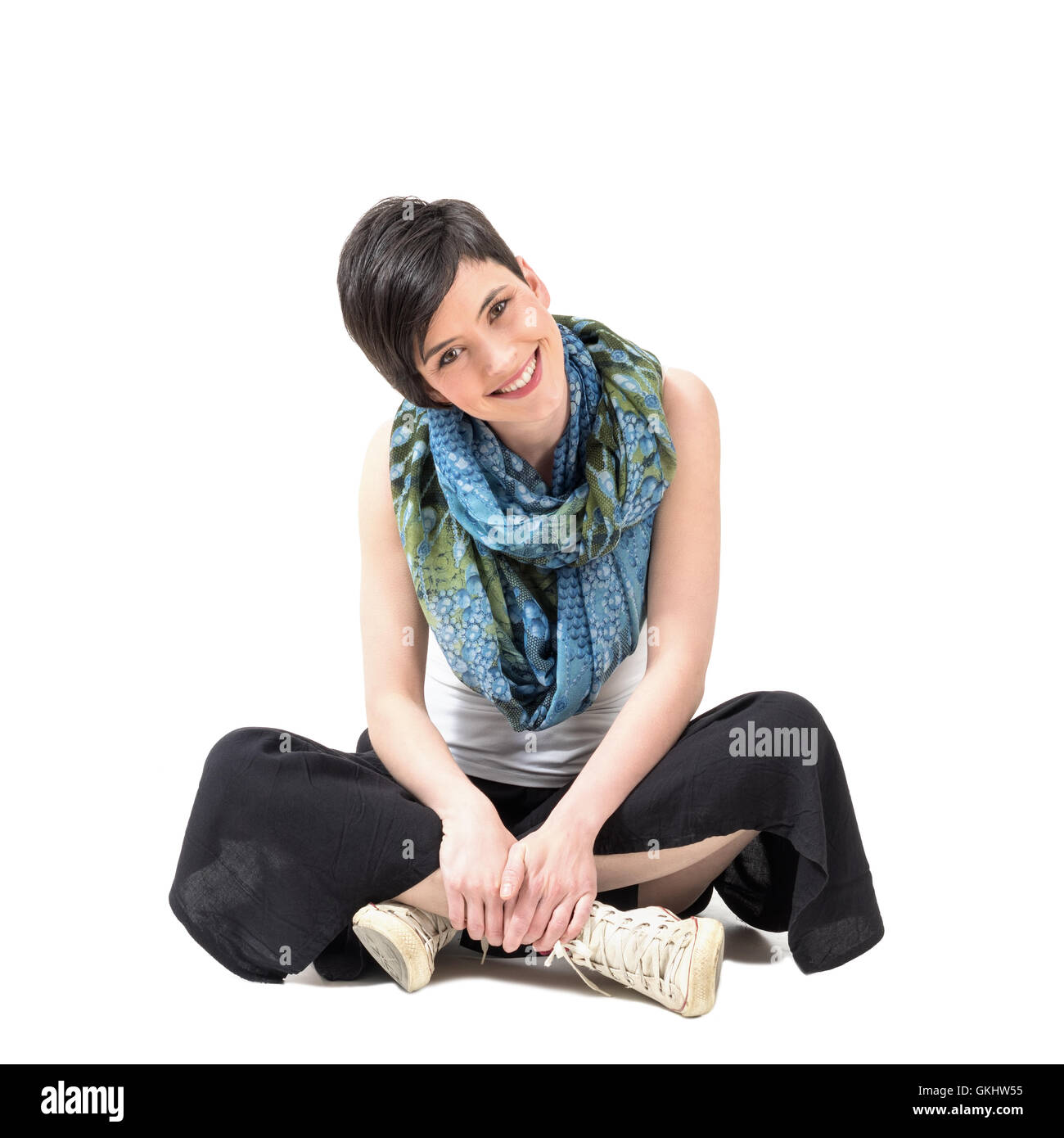 Charming pretty girl sitting cross-legged smiling at camera with ...