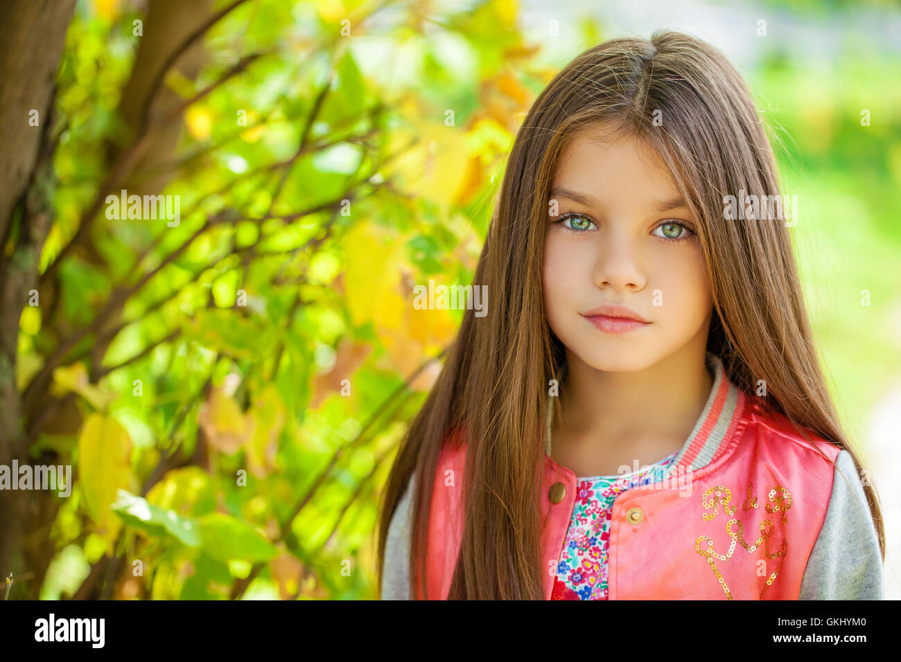 Cose up, Beautiful little girl on green background of summer city park ...