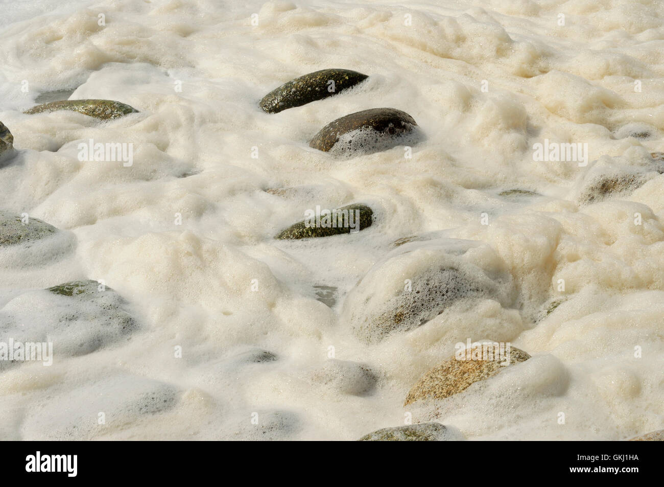 Foam covering coastal rocks after a storm Stock Photo - Alamy