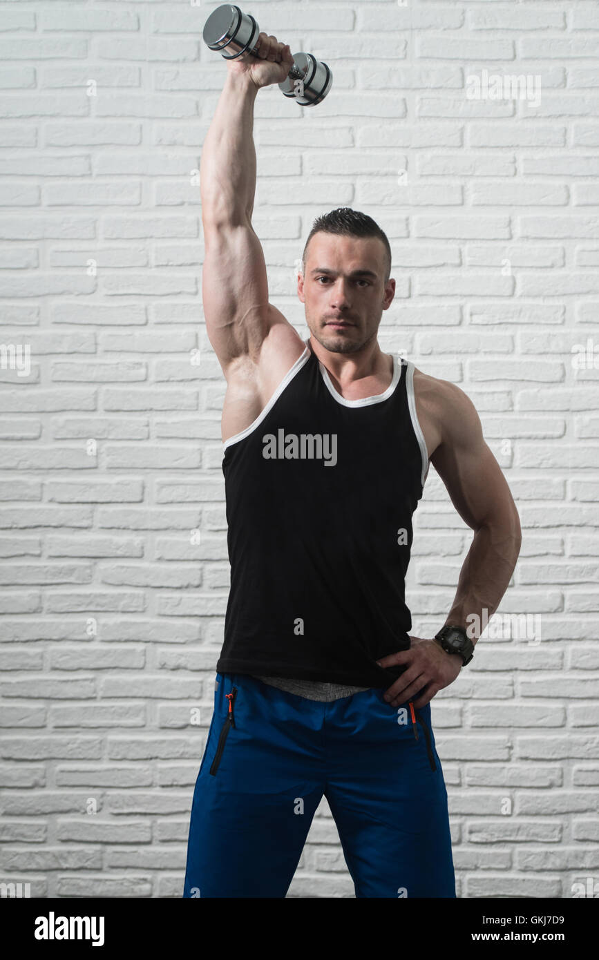 Bodybuilder Working Out Triceps With Dumbbells On White Bricks ...