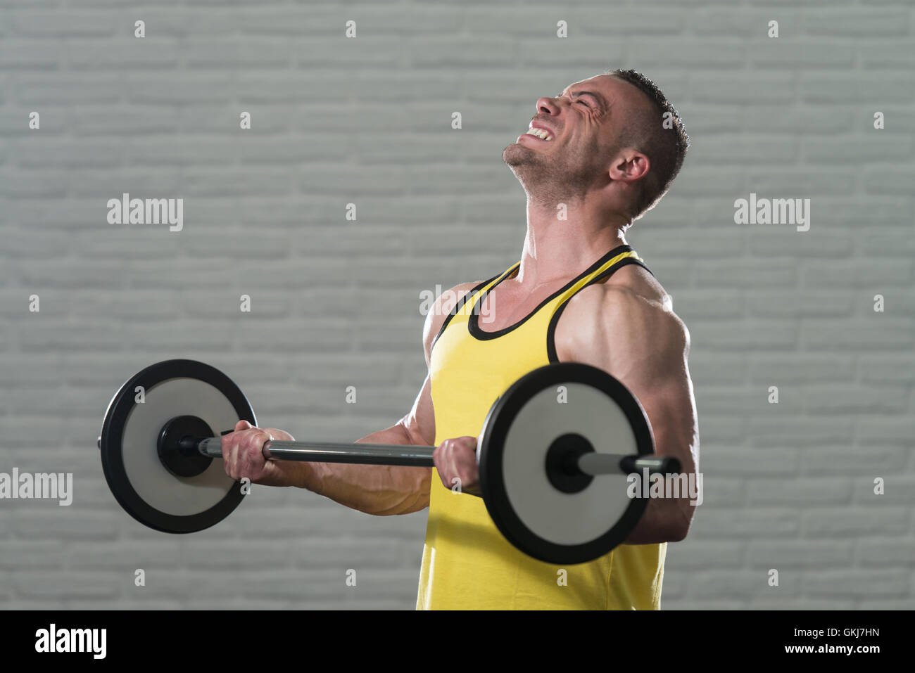 Muscular Man Doing Heavy Weight Exercise For Biceps With Barbell In Gym ...