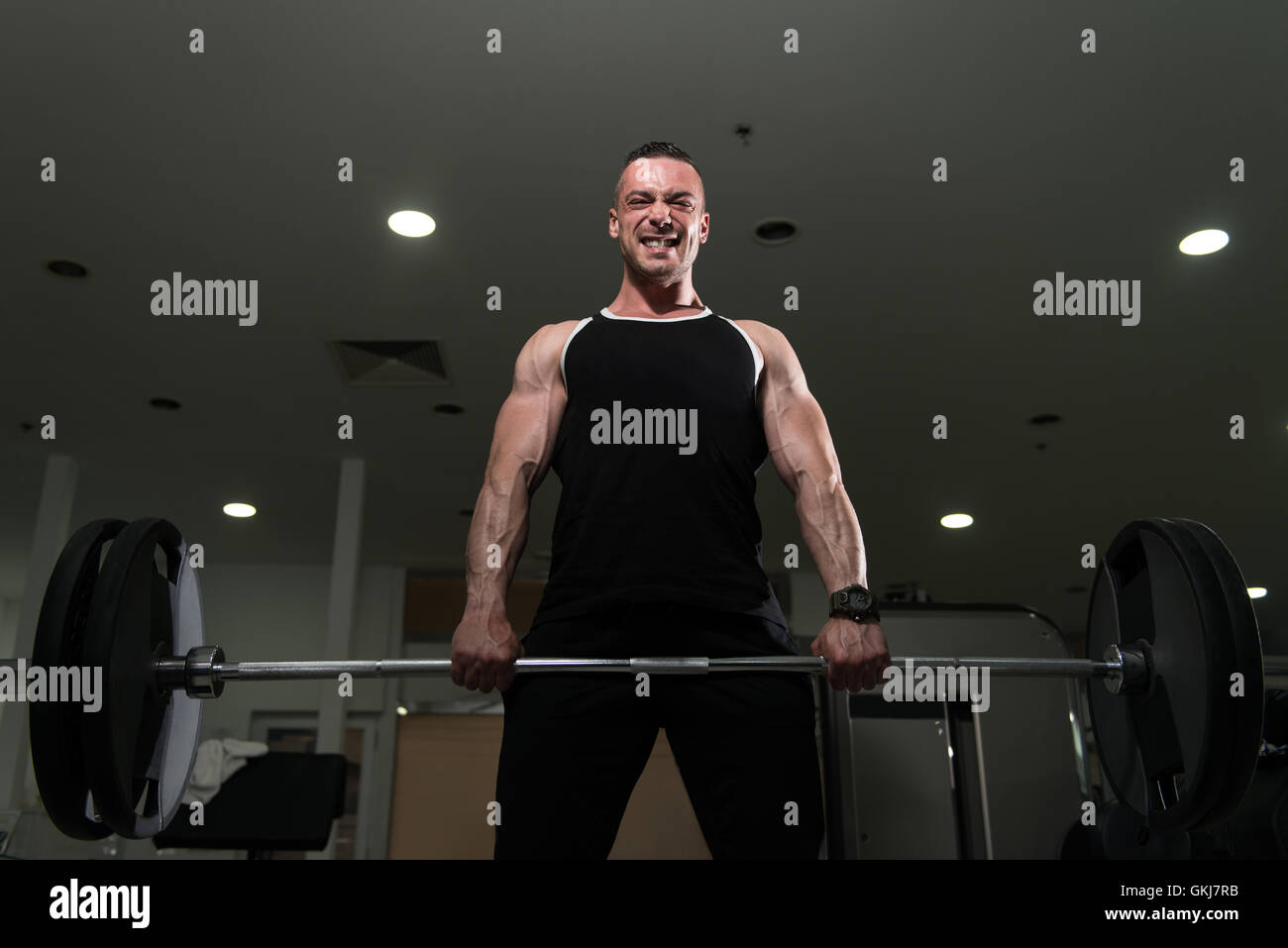 Young Bodybuilder Doing Heavy Weight Exercise For Back With Barbell In ...