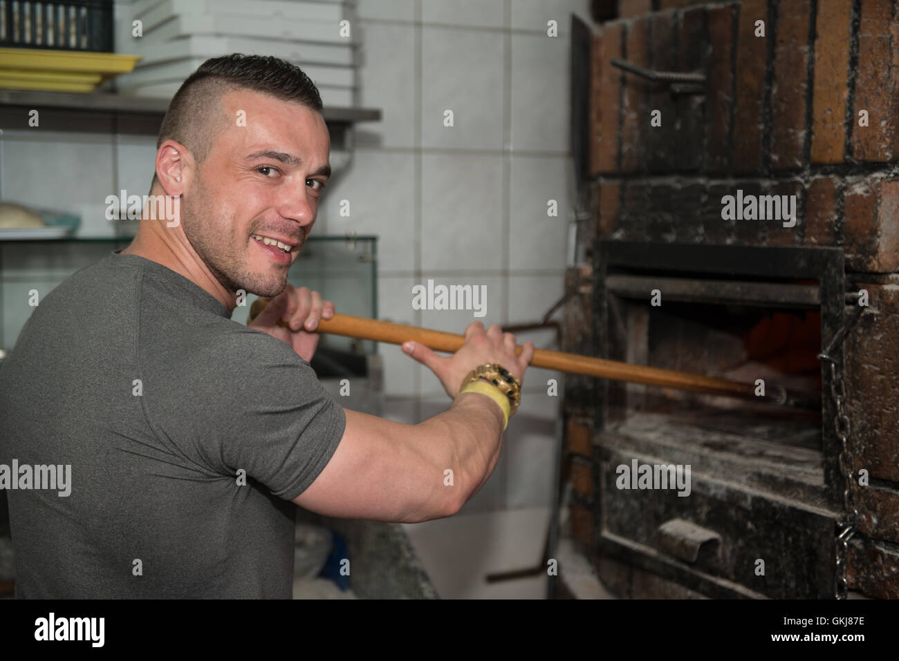 Young Man Cook Putting Pizza Into The Oven With Shovel At Restaurant ...