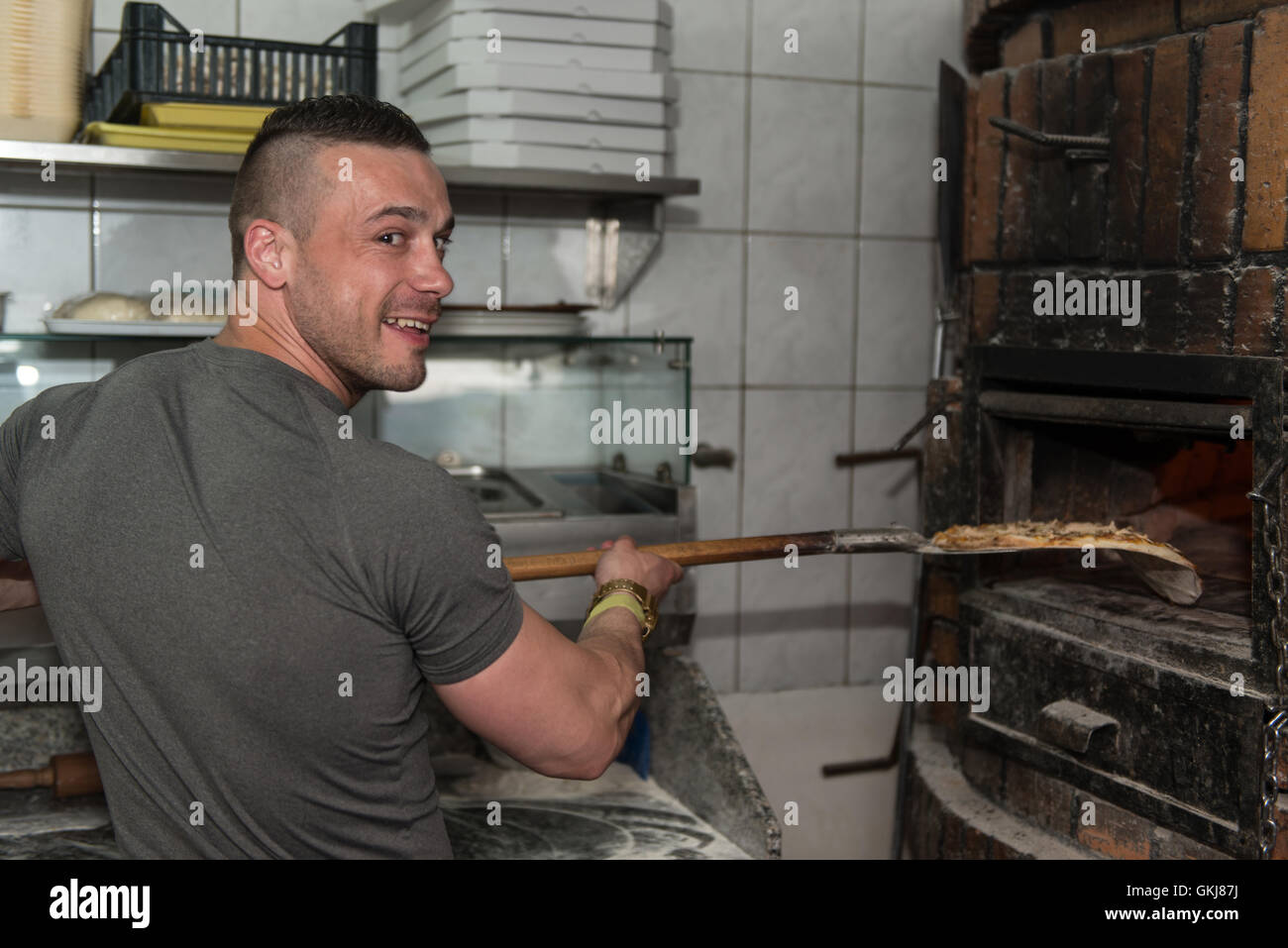 Young Man Cook Putting Pizza Into The Oven With Shovel At Restaurant ...