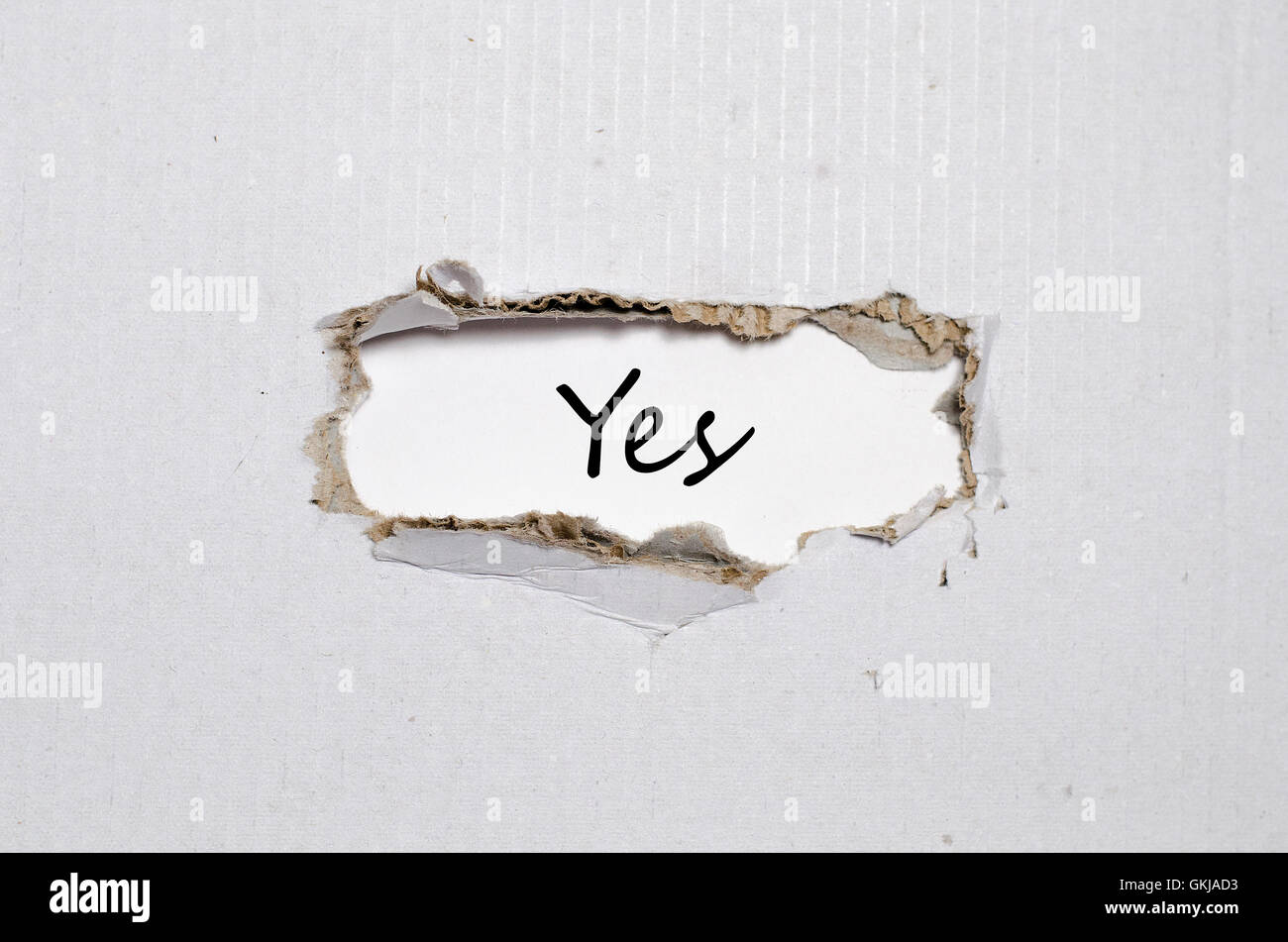 The word yes appearing behind torn paper Stock Photo - Alamy