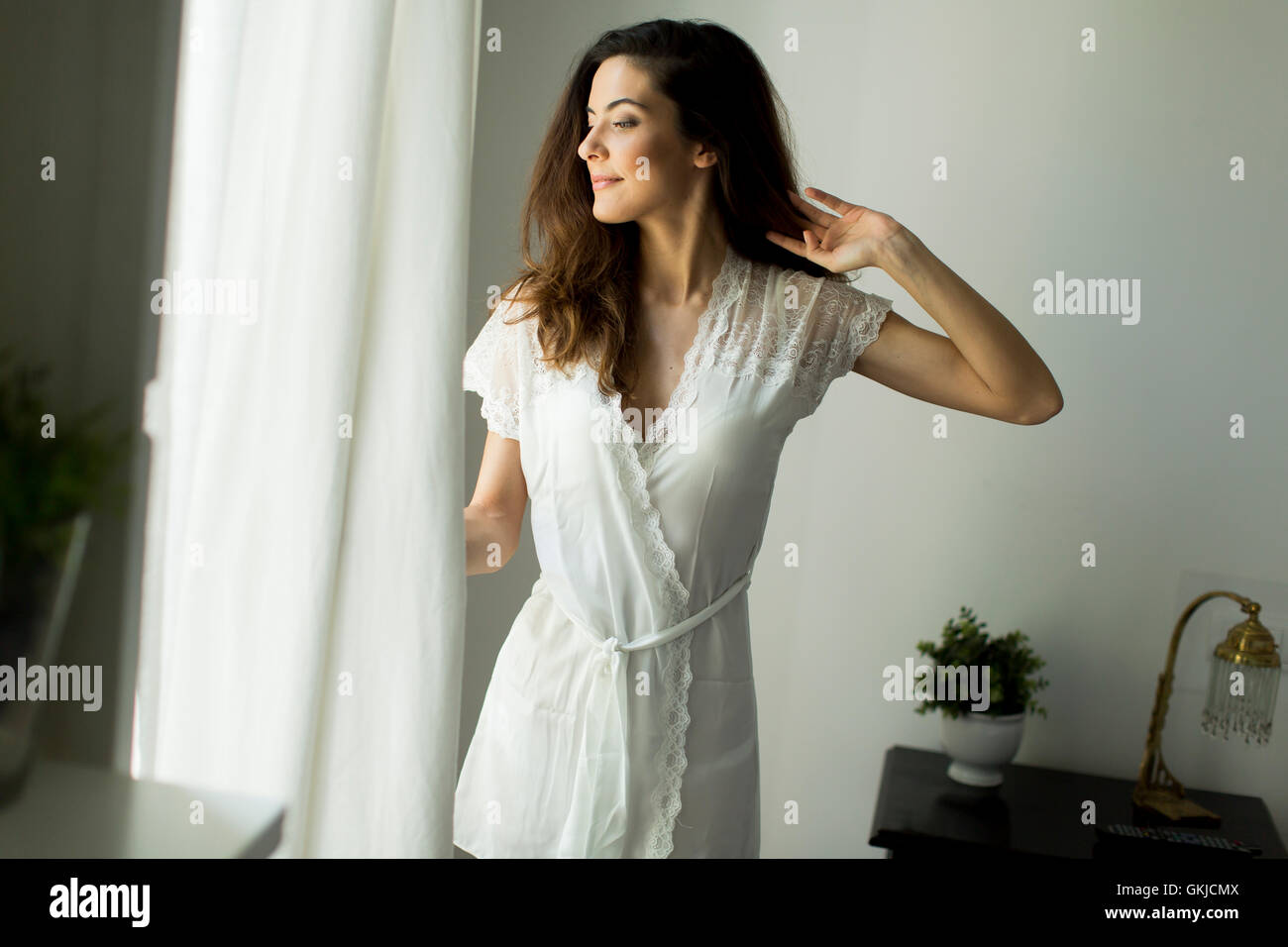 Pretty young woman by the window in the room Stock Photo - Alamy