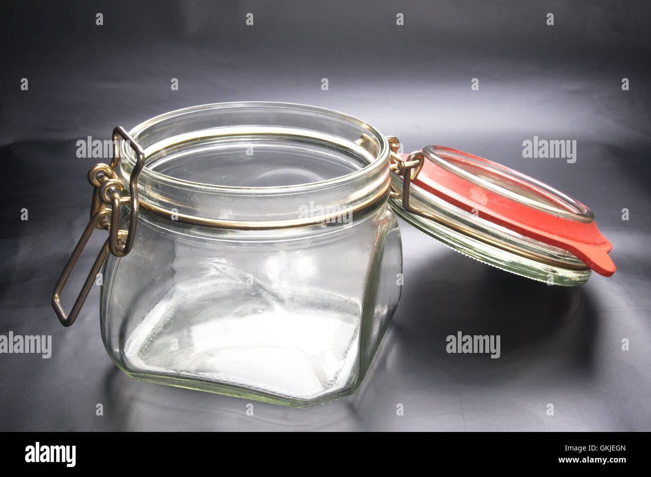 Empty glass jar with the open cap hold with metal wire over the black ...
