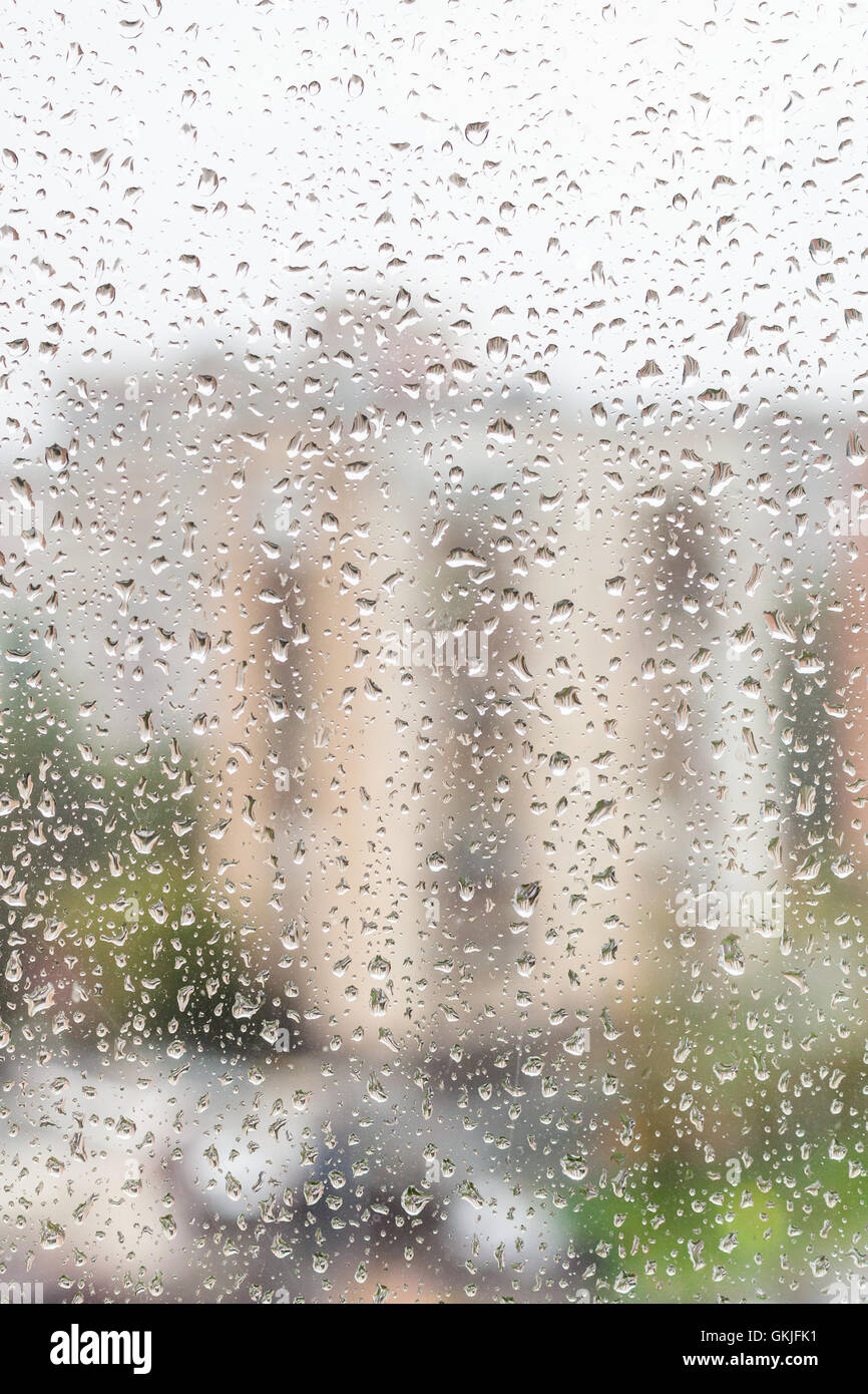rainy weather in city - view of raindrops on window of apartment house ...