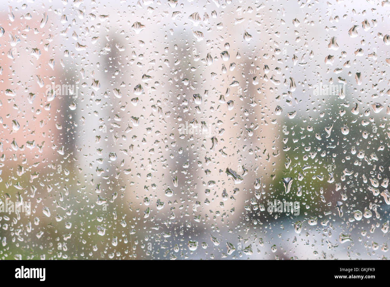 rainy weather in city - view of rain drops on window pane of urban ...