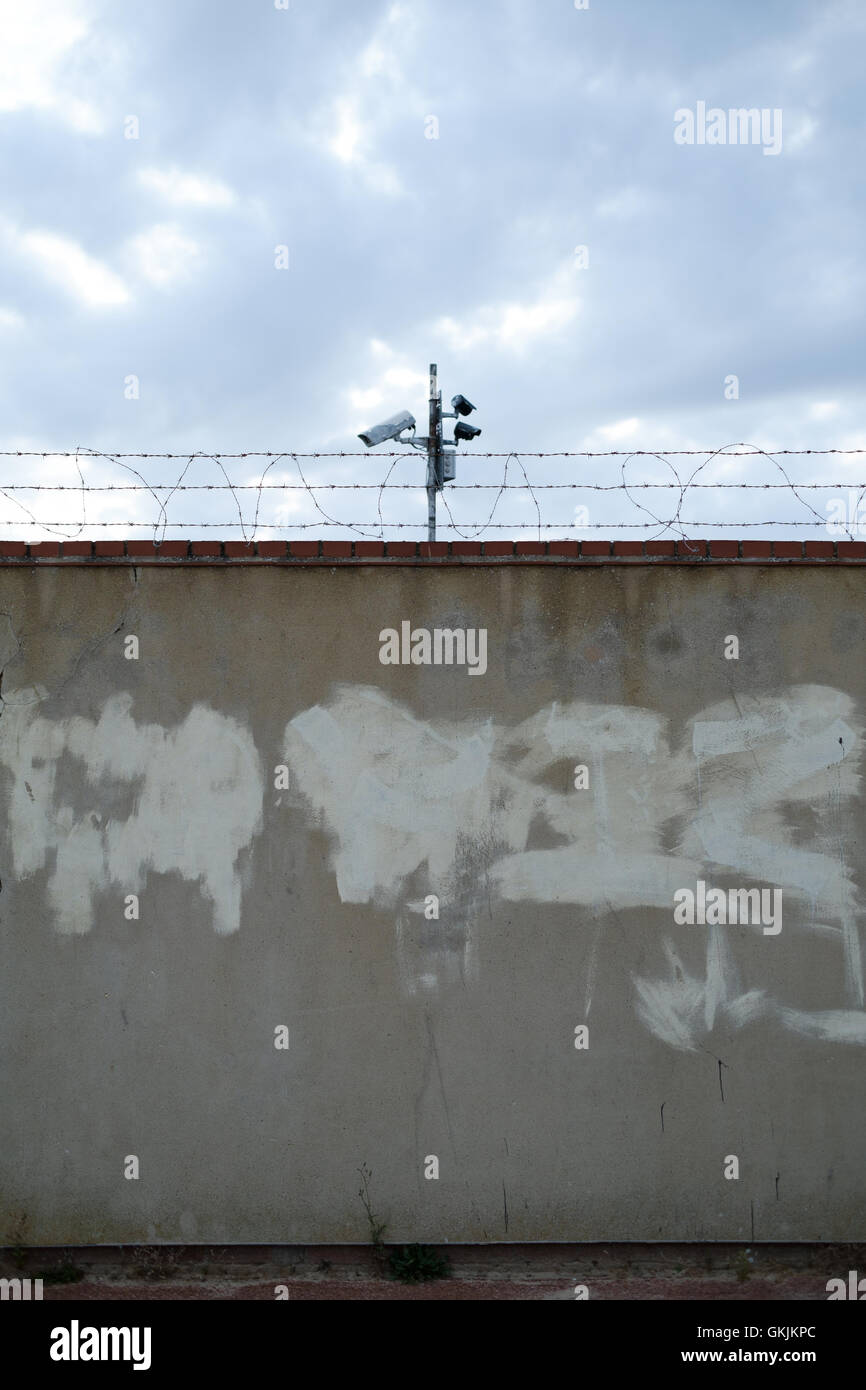 CCTV Surveillance Camera behind warbed wall Stock Photo - Alamy