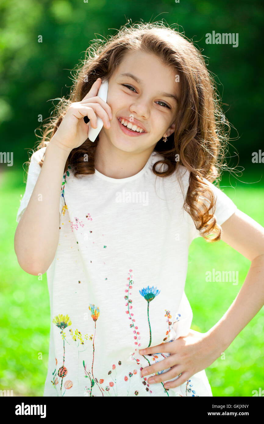 Beautiful little girl calling by mobile phone on the background of ...