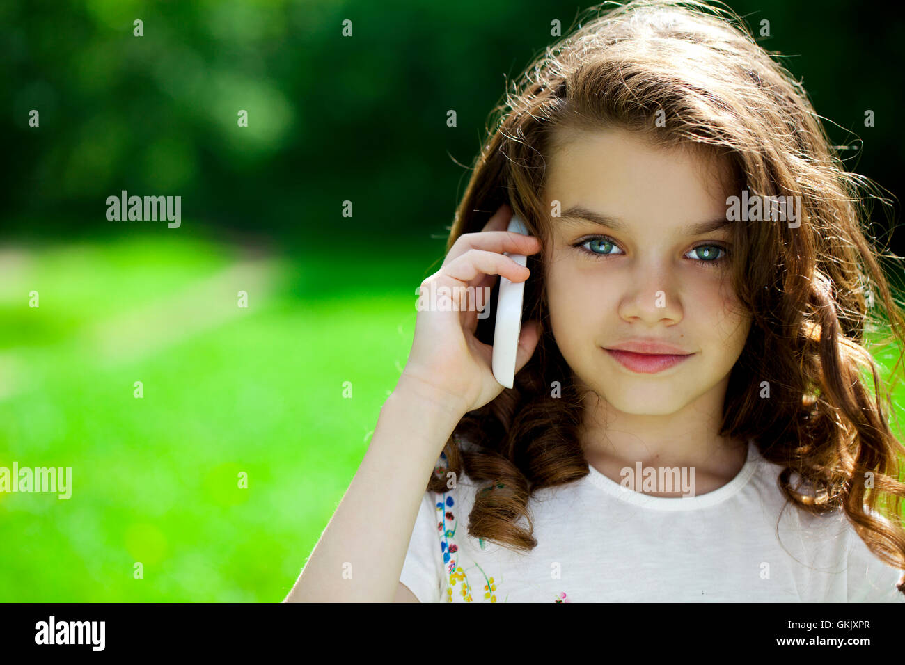 Beautiful little girl calling by mobile phone on the background of ...