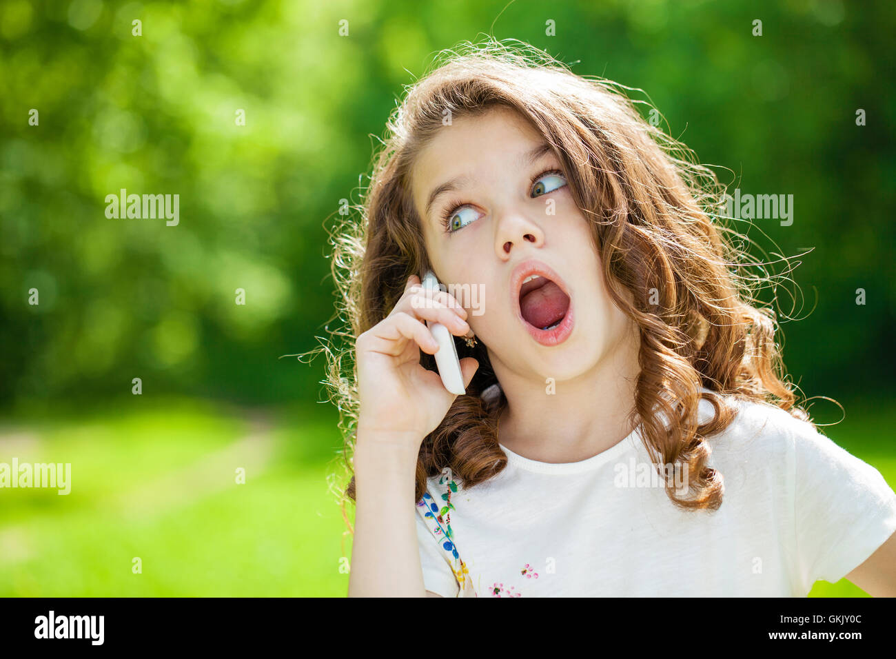Beautiful little girl calling by mobile phone on the background of ...