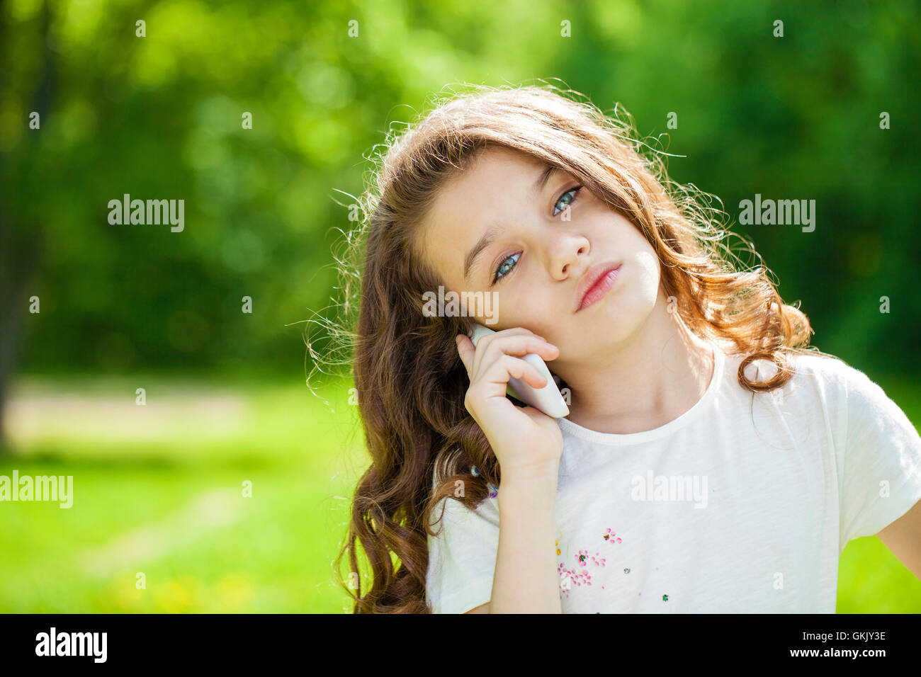 Beautiful little girl calling by mobile phone on the background of ...