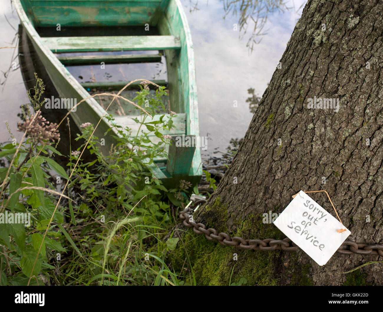 Tethered with a steel chain half sunk old boat, information message in ...