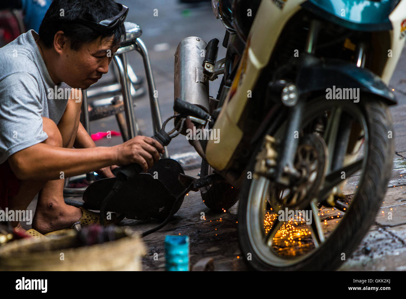 A street welder welding in Hanoi Vietnam on a Moped Motorcycle Stock ...