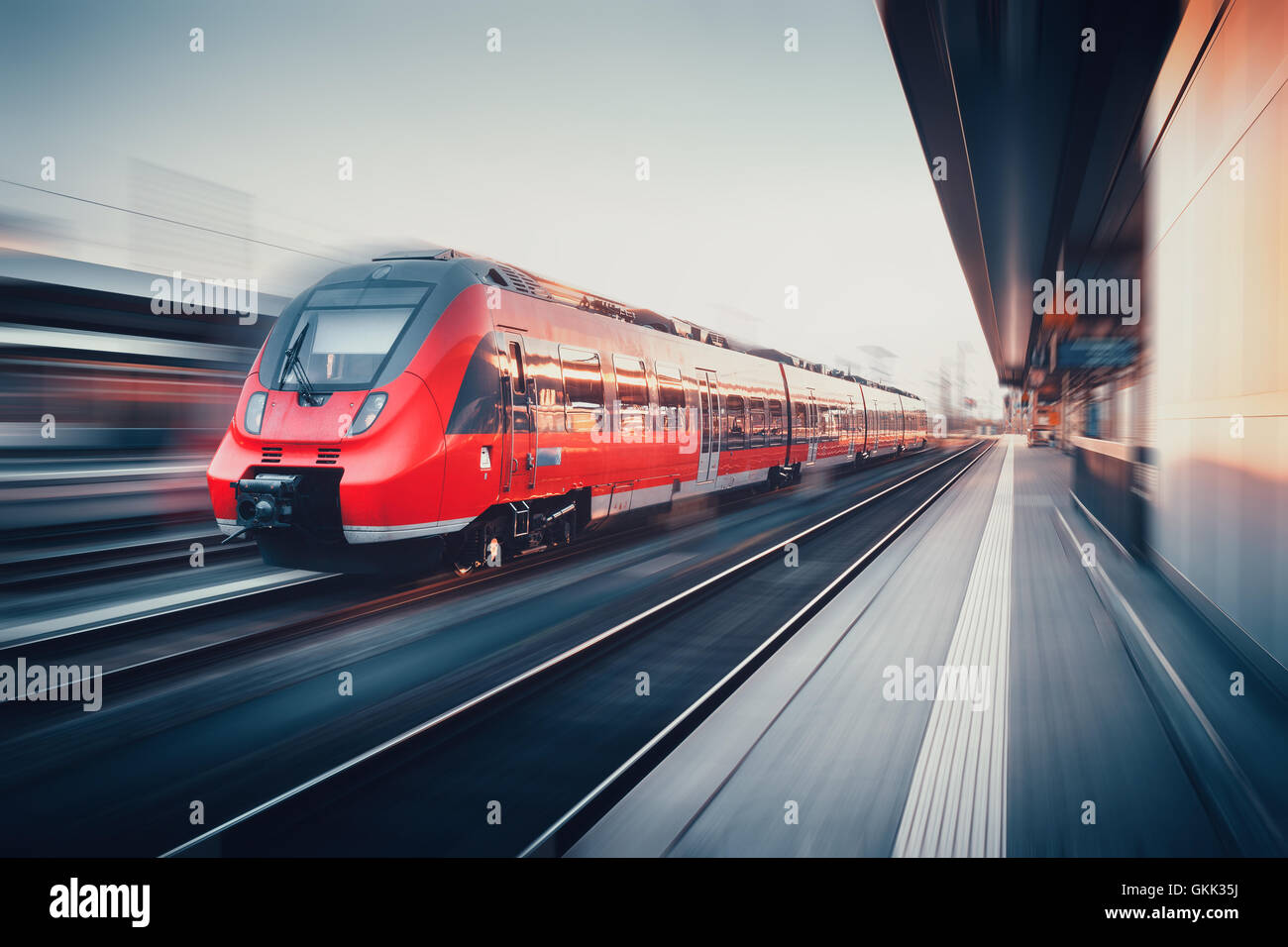 Beautiful railway station with modern high speed red commuter train ...