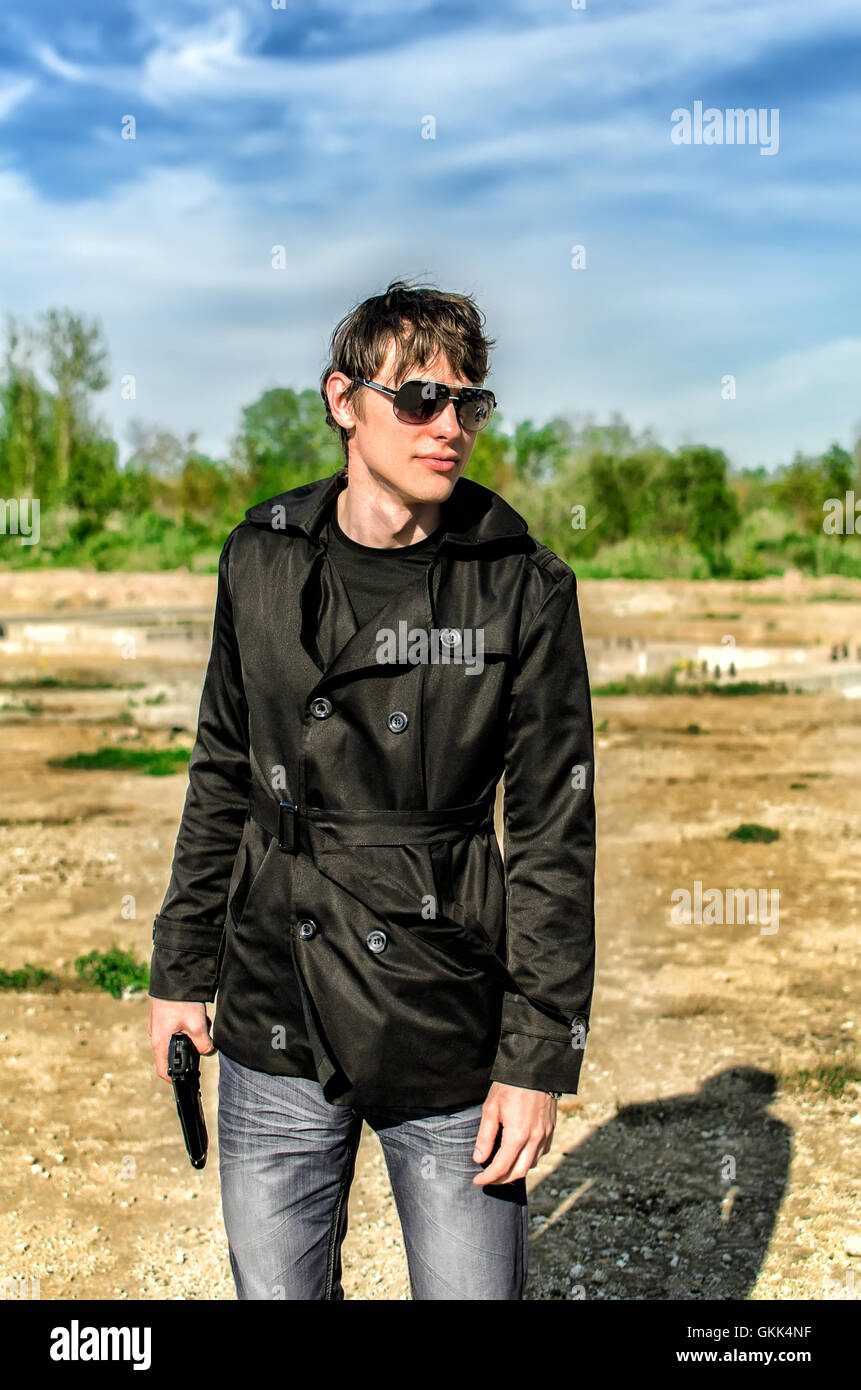 Portrait of an assassin with a gun in glasses Stock Photo - Alamy