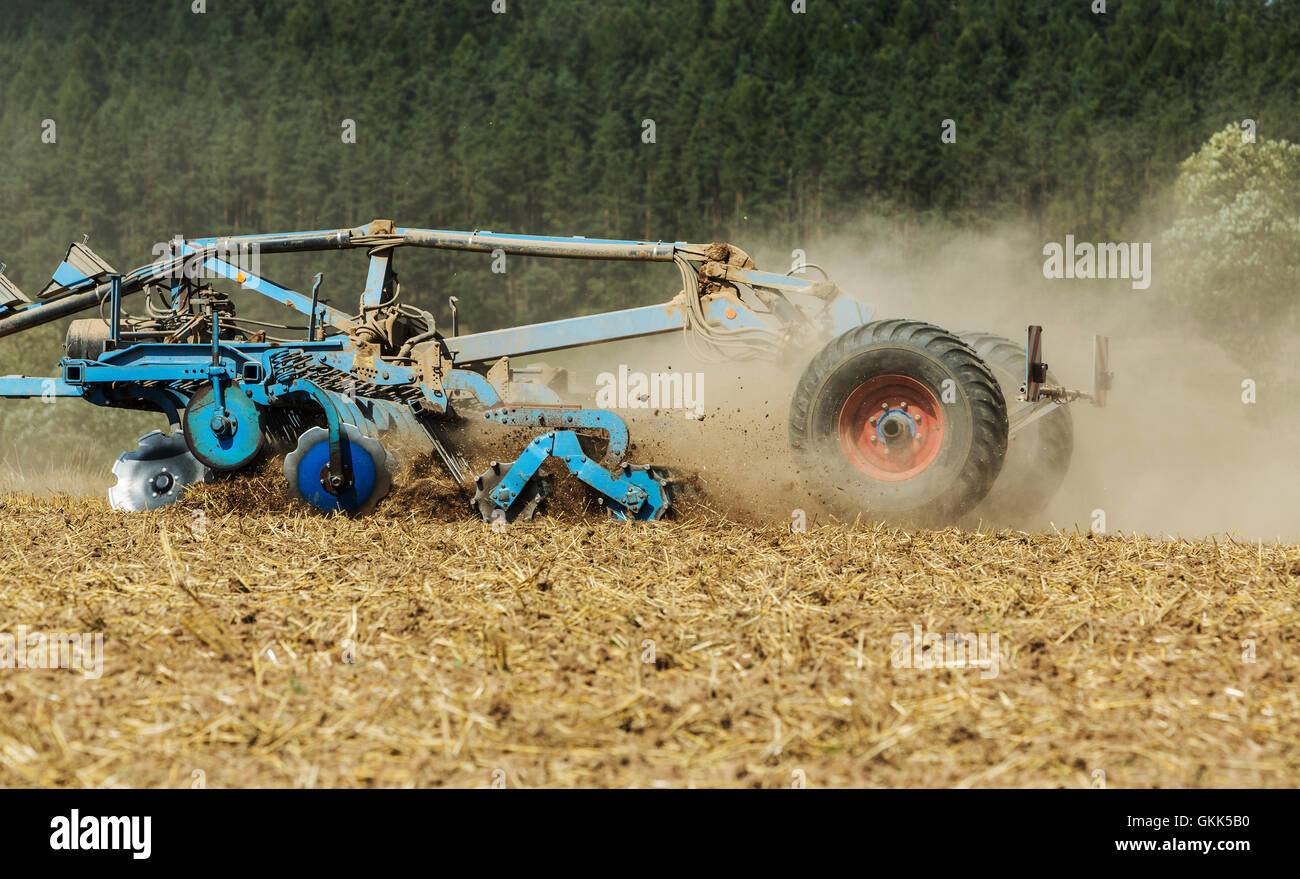 Tractor cultivating field at spring. Tractor with cultivator handles ...