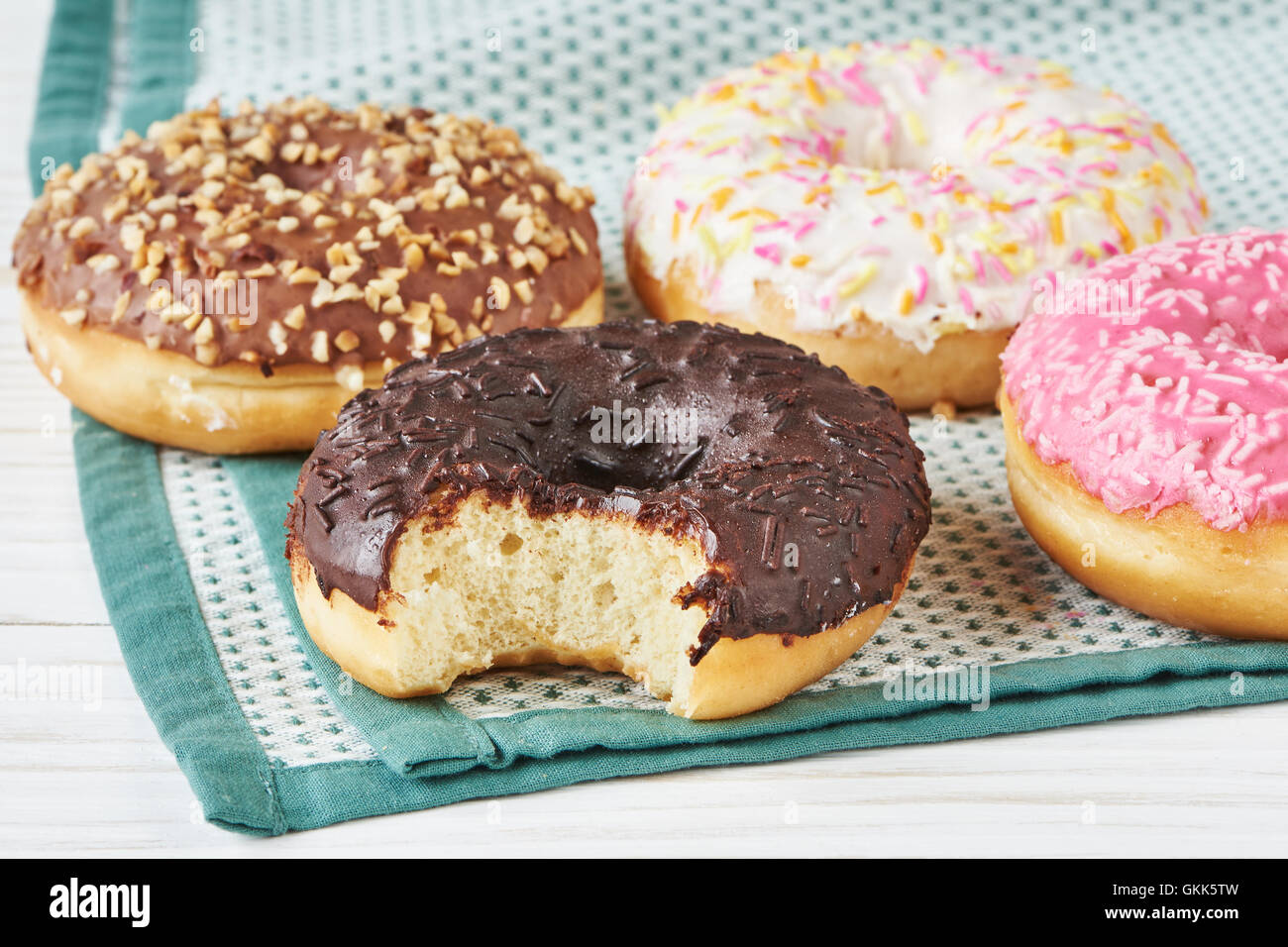 Four colored donut on white wooden background Stock Photo - Alamy