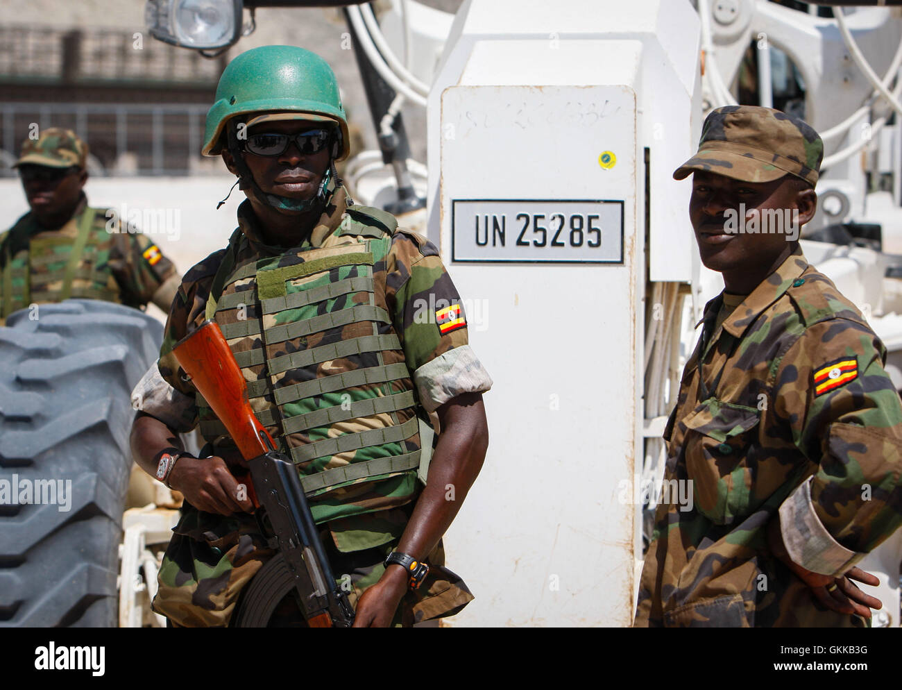 Ugandan soldiers with AMISOM stand beside an earth grader as they clear ...