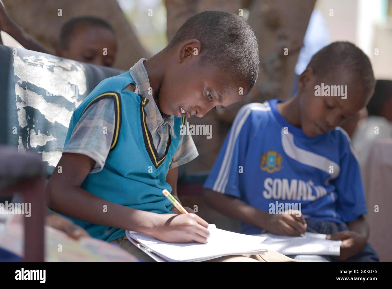 A young boy takes notes during a class session at Somali Orphans ...