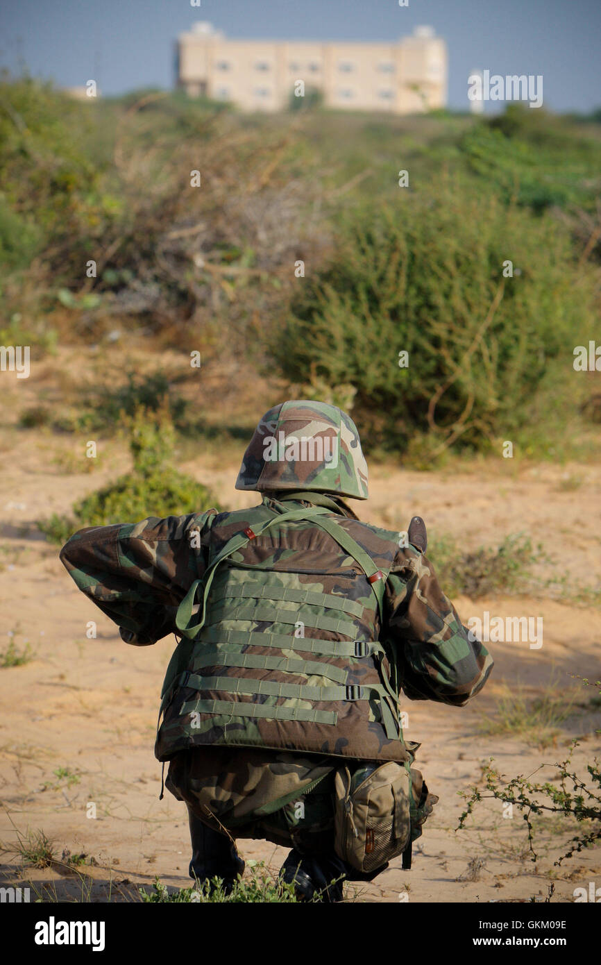 On January 20, a Ugandan soldier serving with AMISOM crouches during an ...