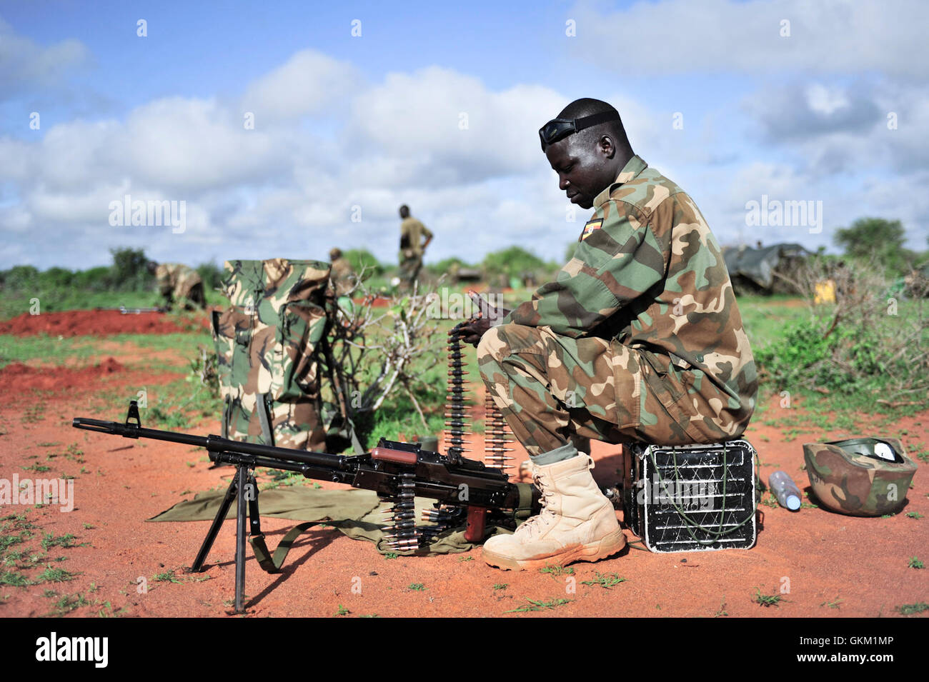 A Ugandan machine gunner cleans his weapon before joining a convoy ...