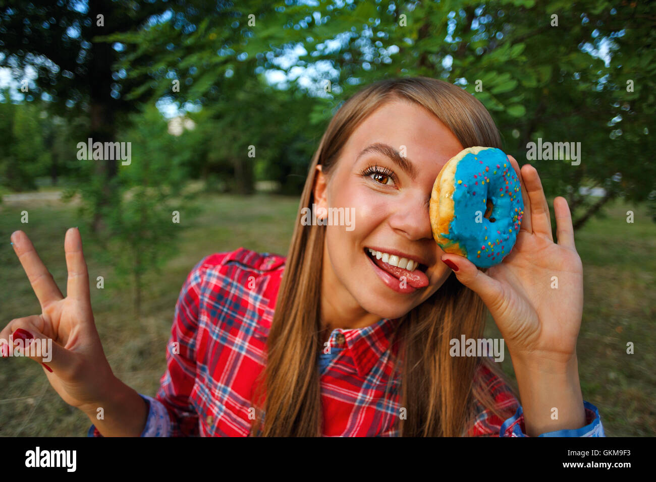Funny girl holding a donut in hand, closing one eye. Delicious Stock ...