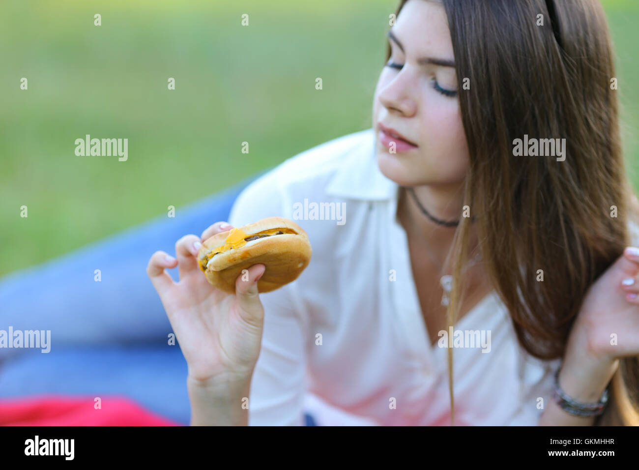 girl lying on the nature and eateth fast food. student working in the ...