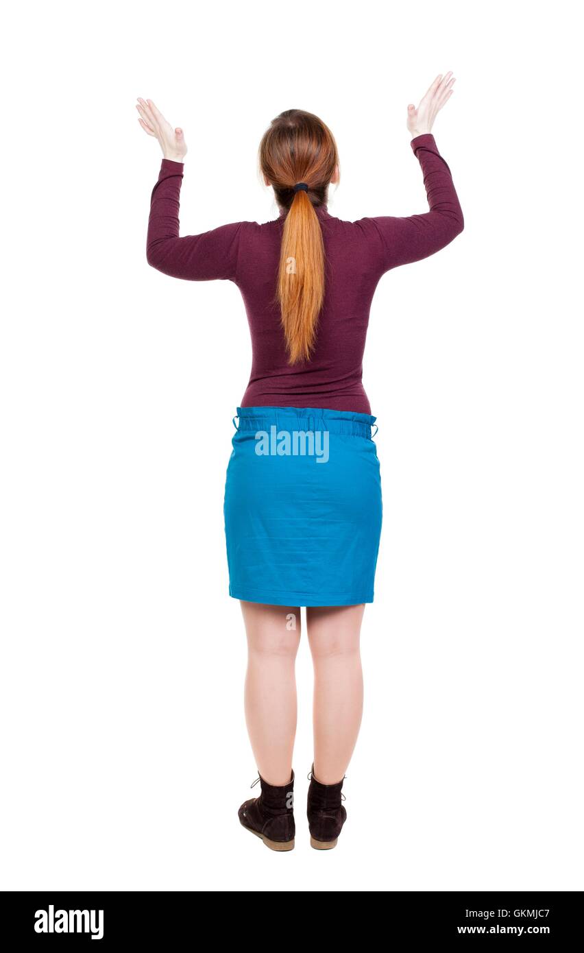 Back view of Beautiful woman in jeans looking at wall and Holds hand up ...