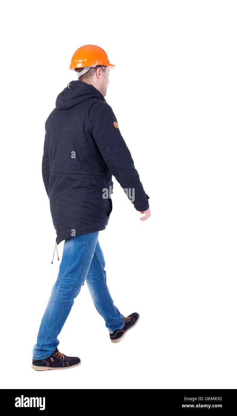 Back view of goingWorker in a helmet. walking young engineer. Rear view ...
