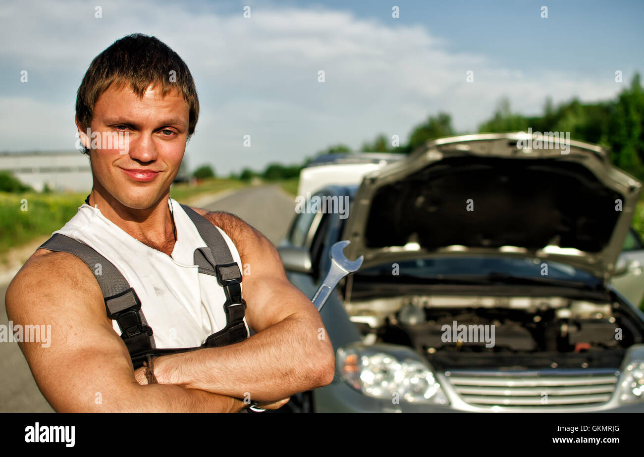 Portrait of a hadsome mechanic with a broken car on background Stock ...