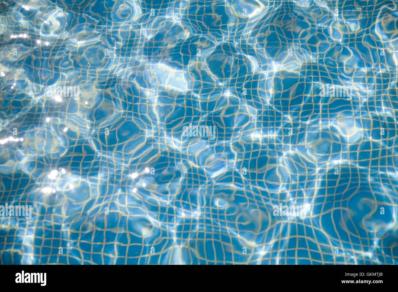 Pure blue transparent water with patches of light from the sun in pool ...