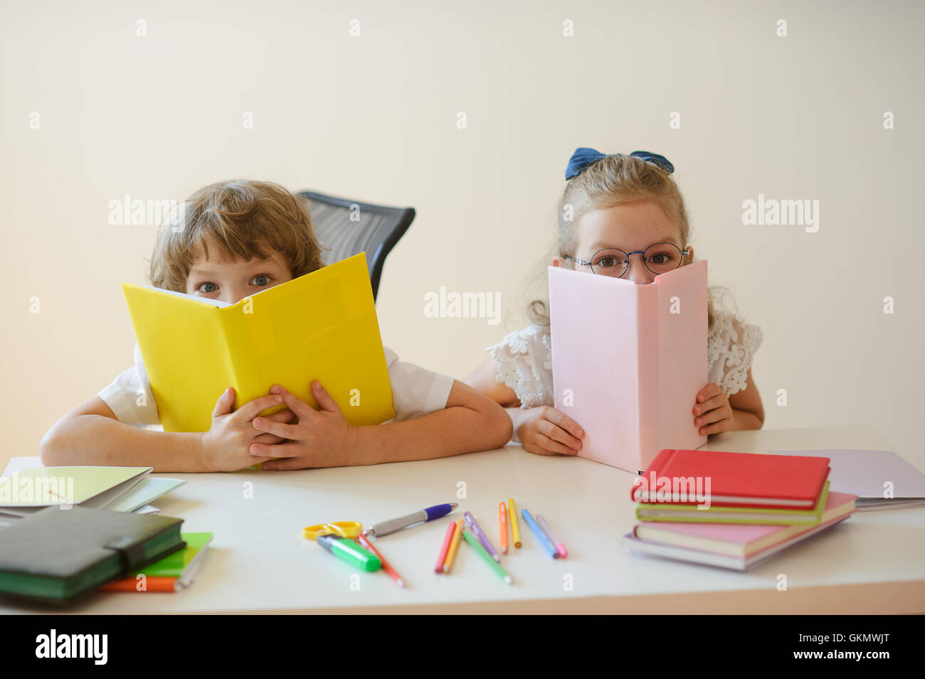 Two young classmate, boy and girl, are sitting at the same desk ...