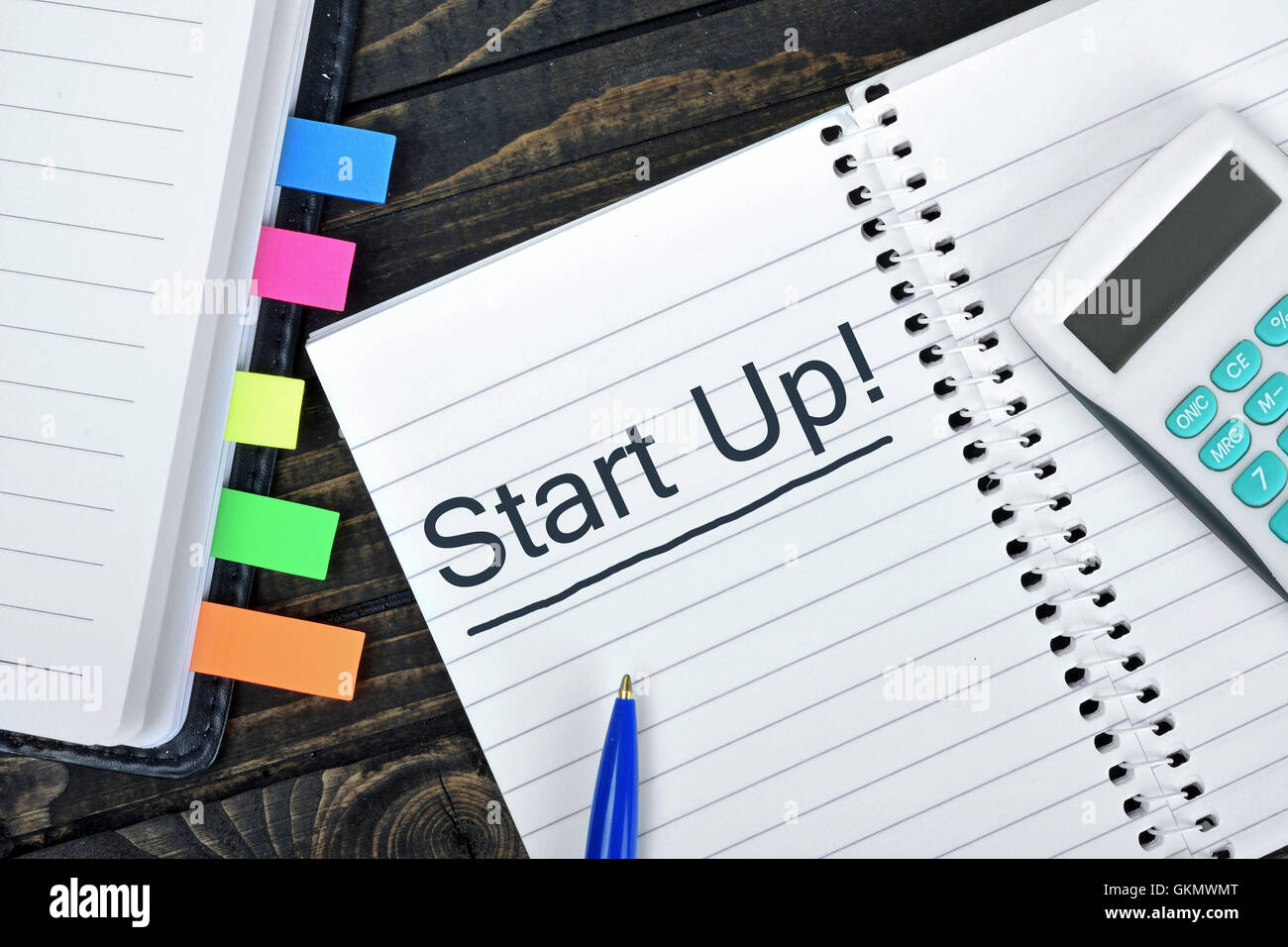 Start up text on notepad and hand calculator Stock Photo - Alamy