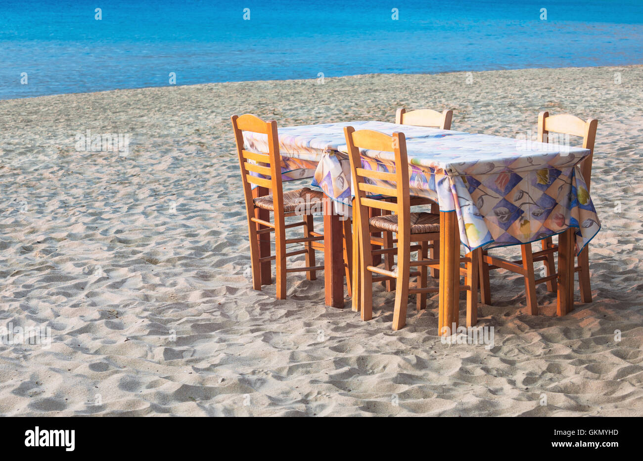 Greek taverna table and chairs on sandy beach Stock Photo - Alamy