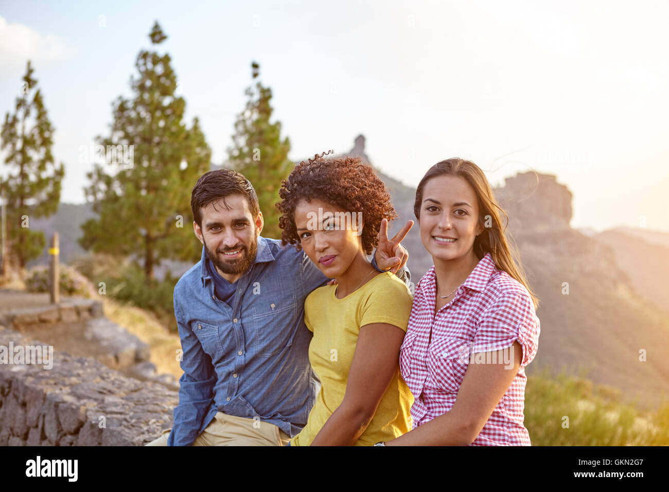 Three friends posing for a picture with mountains behind them while ...