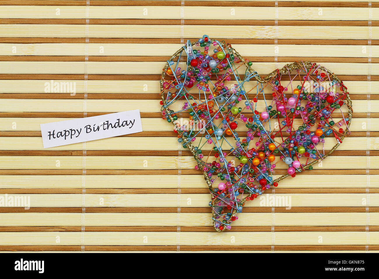 Happy Birthday card with heart made of colorful beads on bamboo mat ...