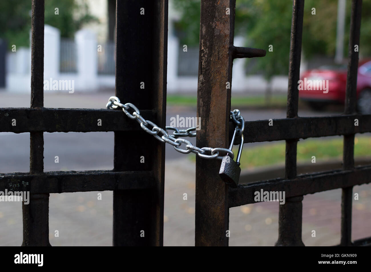 Chain and lock on the iron fence. Closeup view. City street and car ...
