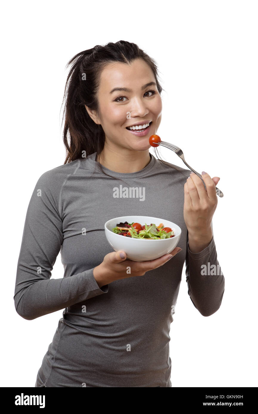 happy fitness model eating a salad shot in the studio on a white ...