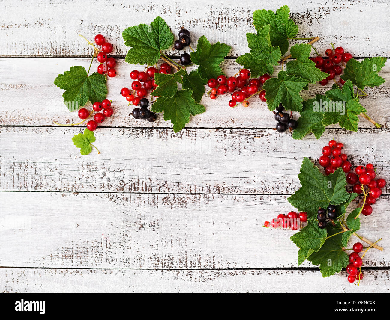 Red and black currant with leaves on a light wooden background. Frame ...
