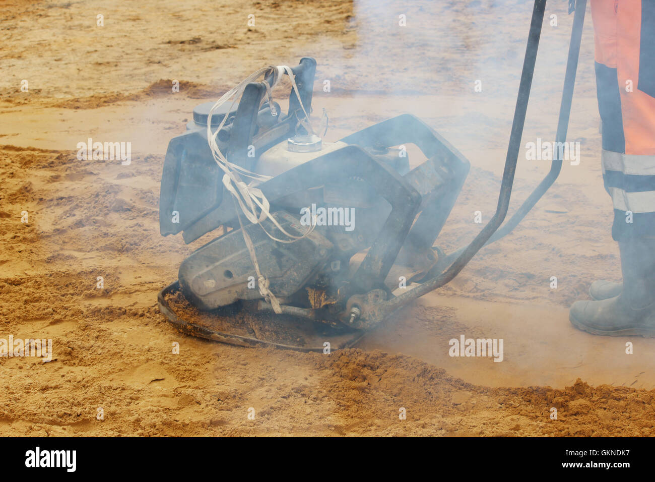 mason tamps the soil using plate compactor before laying paving slabs ...