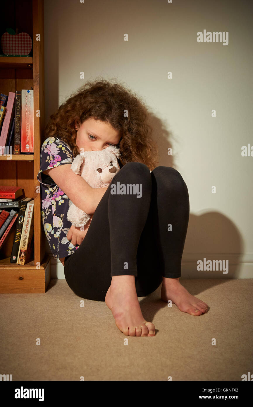 Sad girl curled up on floor hi-res stock photography and images - Alamy