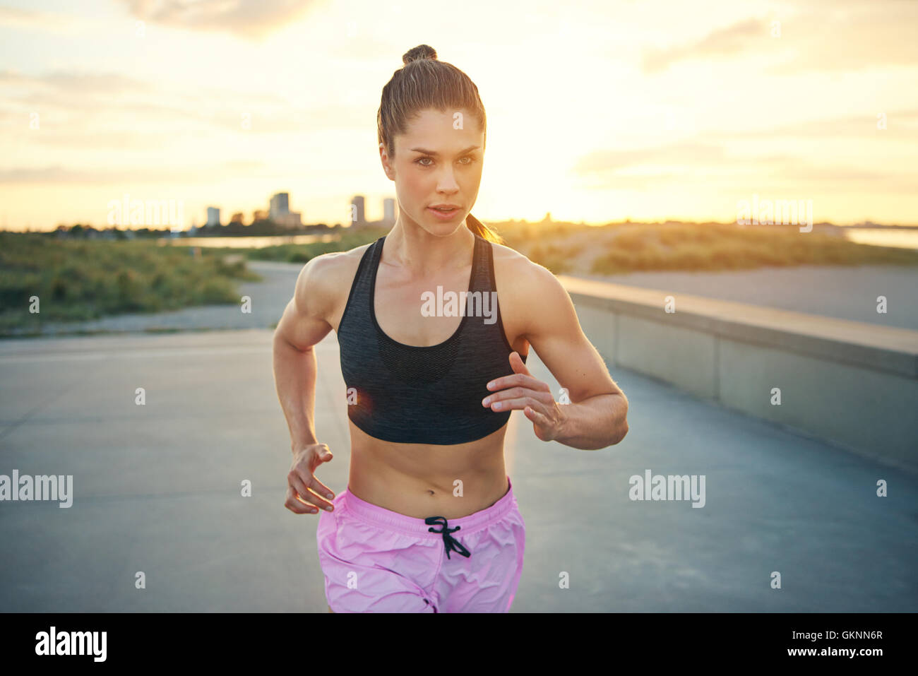 Attractive fit young woman jogger out training at sunrise running ...