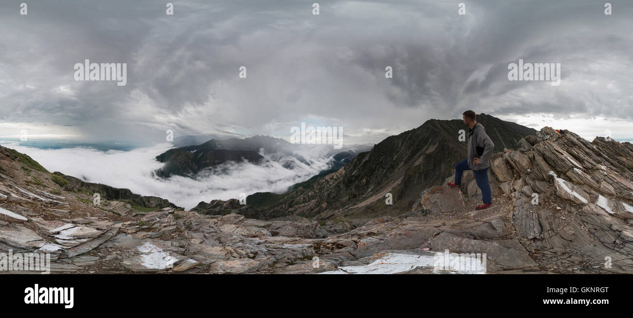 A man stands in the mountains and looks into the distance, panorama ...