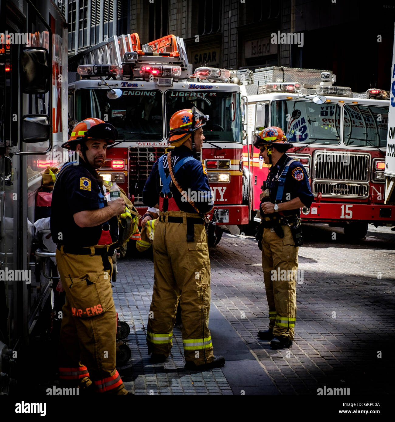 Three New York Firemen on the street by their engines at an incident in ...